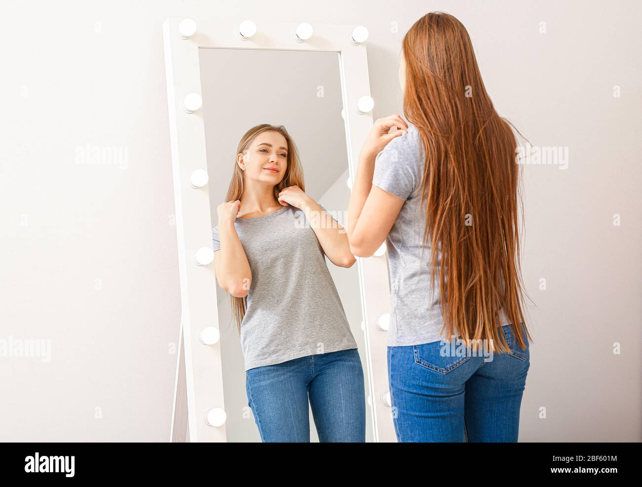 Beautiful young woman looking at her reflection in mirror Stock Photo ...
