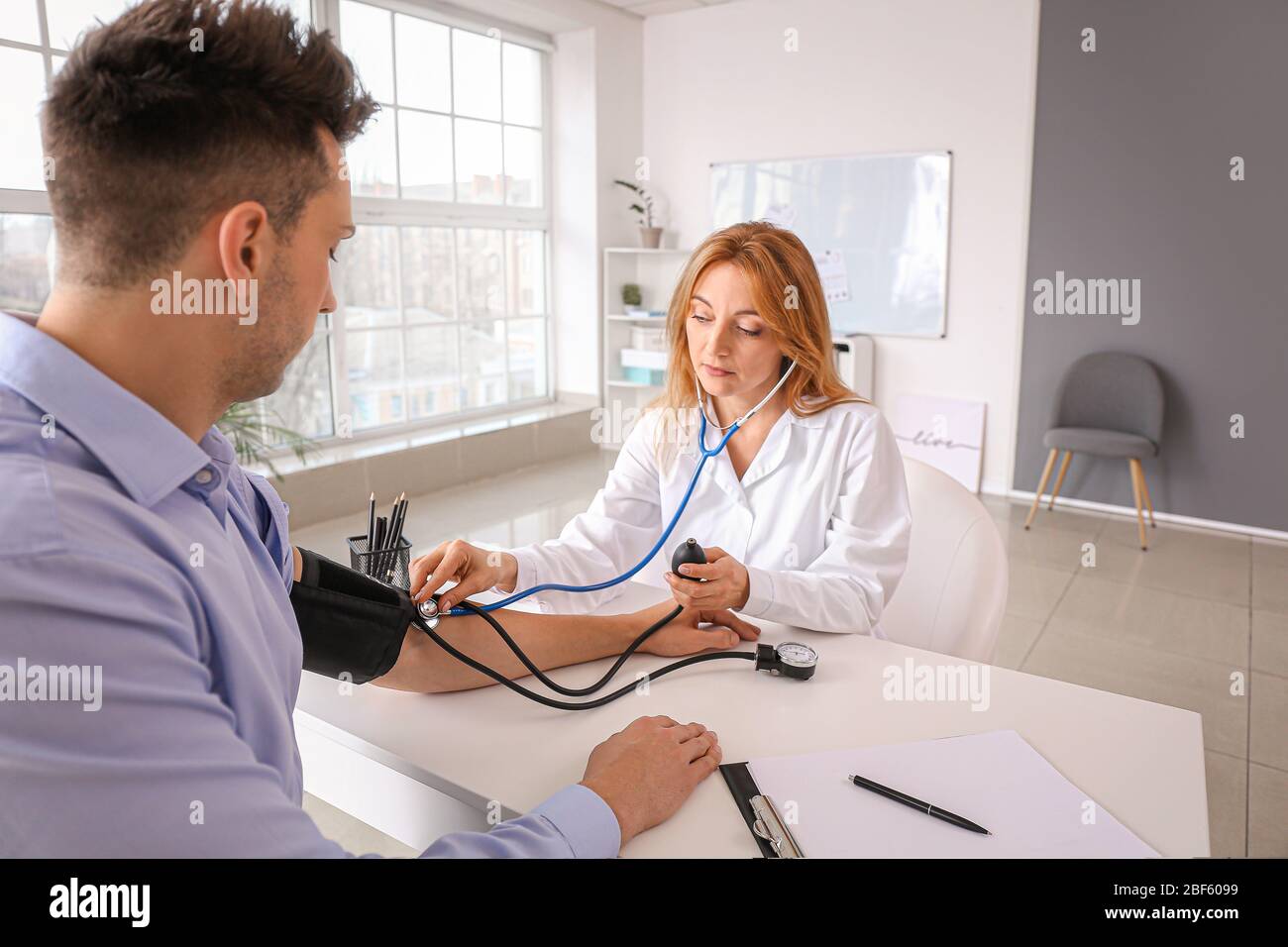Female cardiologist examining male patient in clinic Stock Photo - Alamy