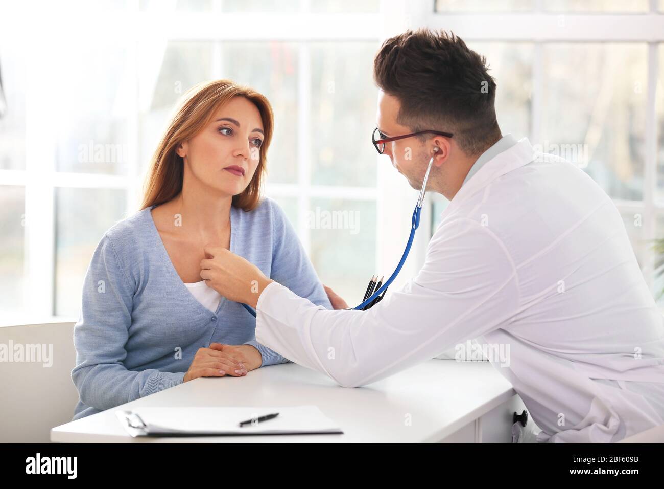 Male cardiologist examining female patient in clinic Stock Photo - Alamy