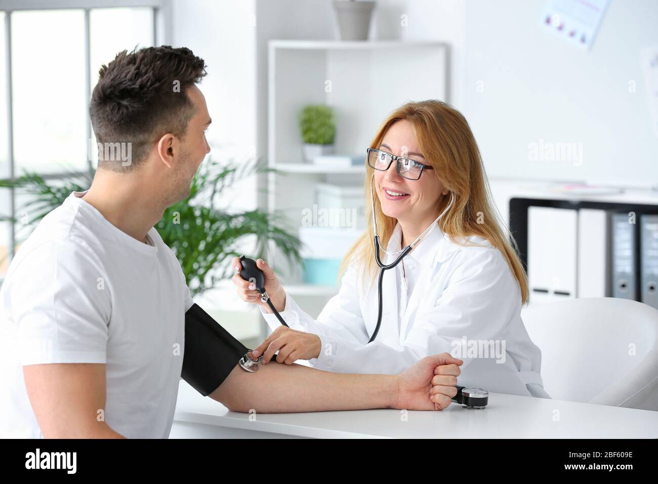 Female cardiologist examining male patient in clinic Stock Photo - Alamy