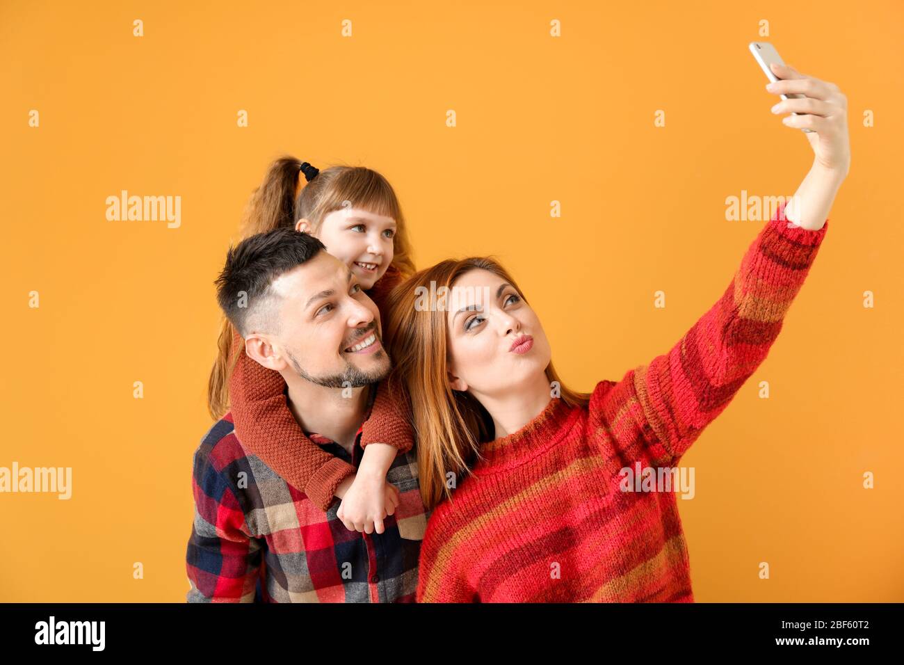 Family taking selfie on color background Stock Photo - Alamy