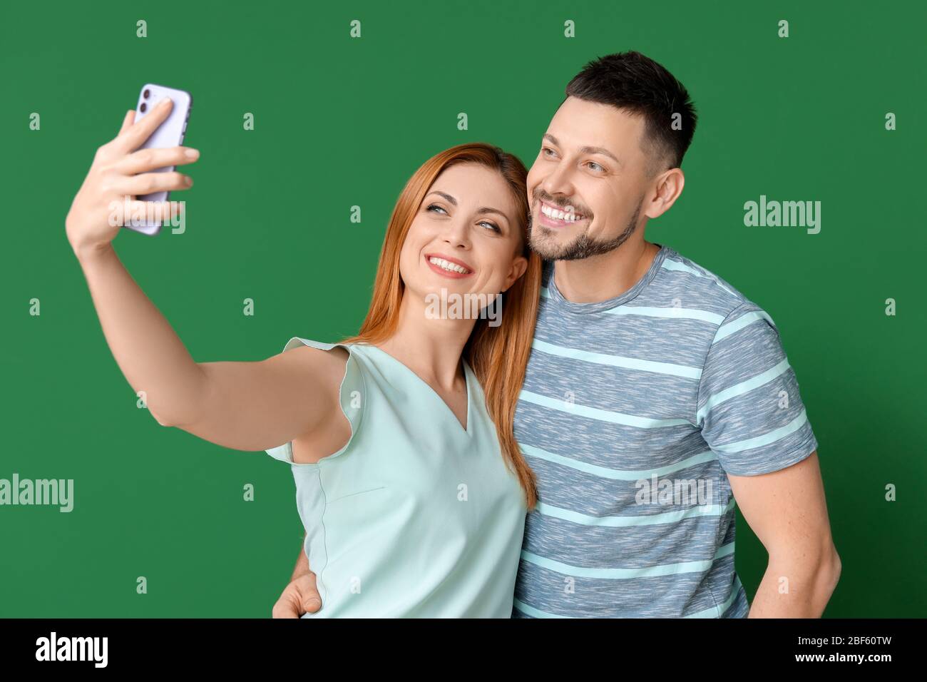 Couple taking selfie on color background Stock Photo - Alamy