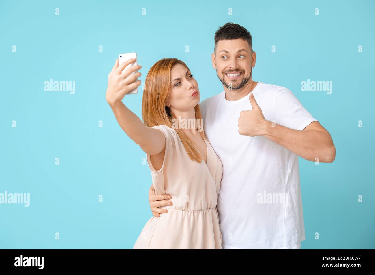 Couple taking selfie on color background Stock Photo - Alamy