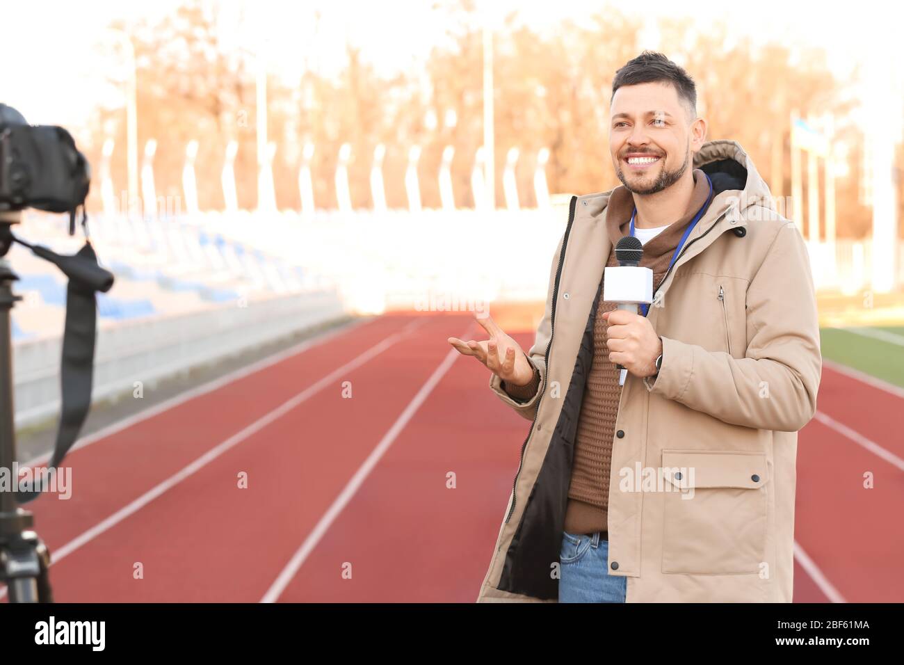 Male reporter with microphone at the stadium Stock Photo - Alamy