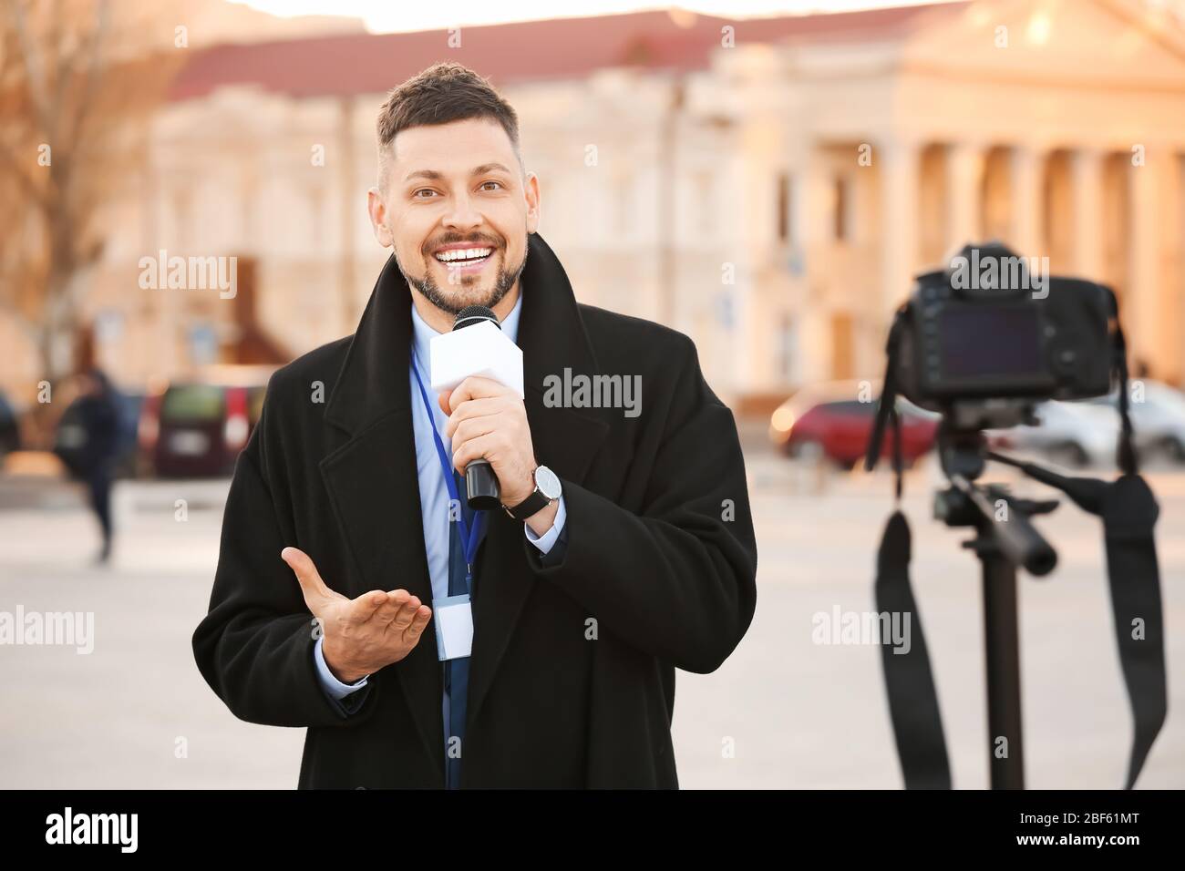 Male journalist with microphone outdoors Stock Photo - Alamy