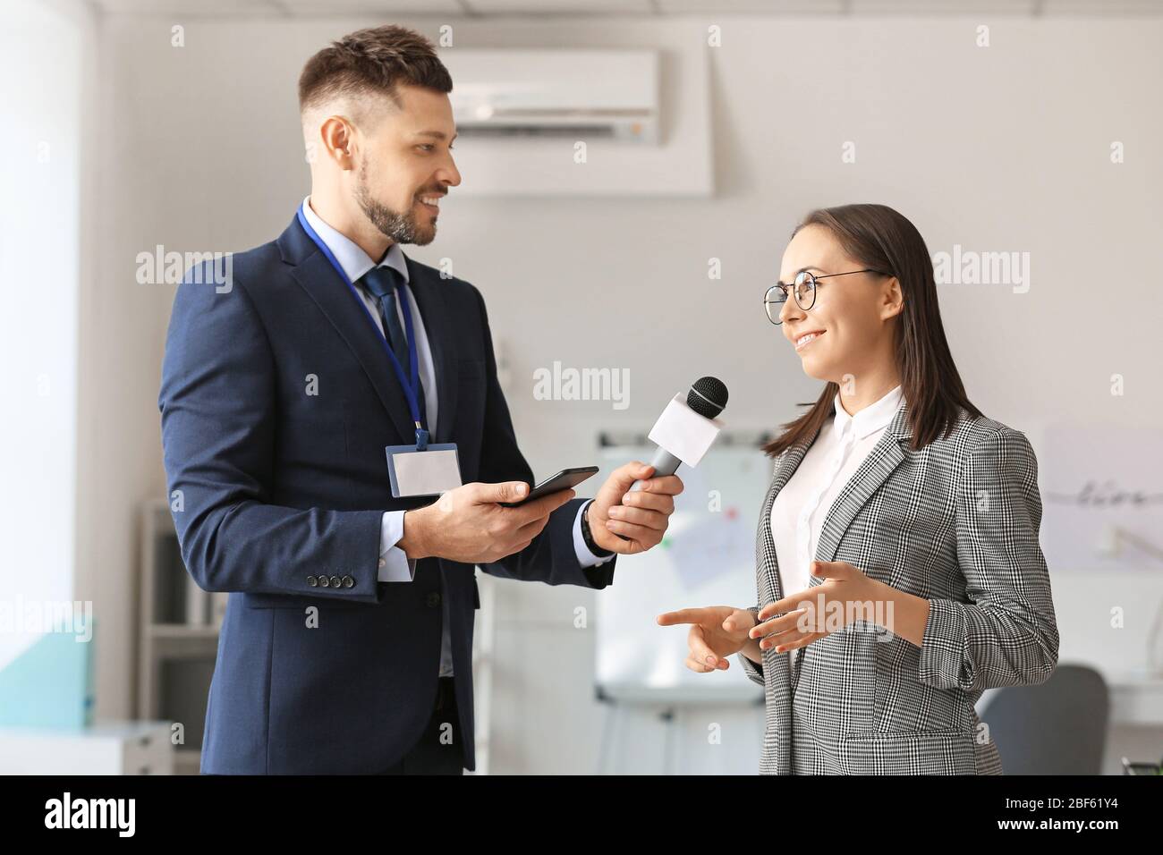 Male journalist having interview with woman indoors Stock Photo - Alamy