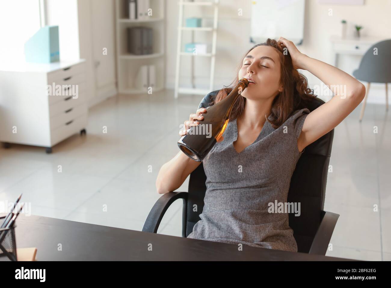 Young drunk woman in office. Concept of alcoholism Stock Photo - Alamy