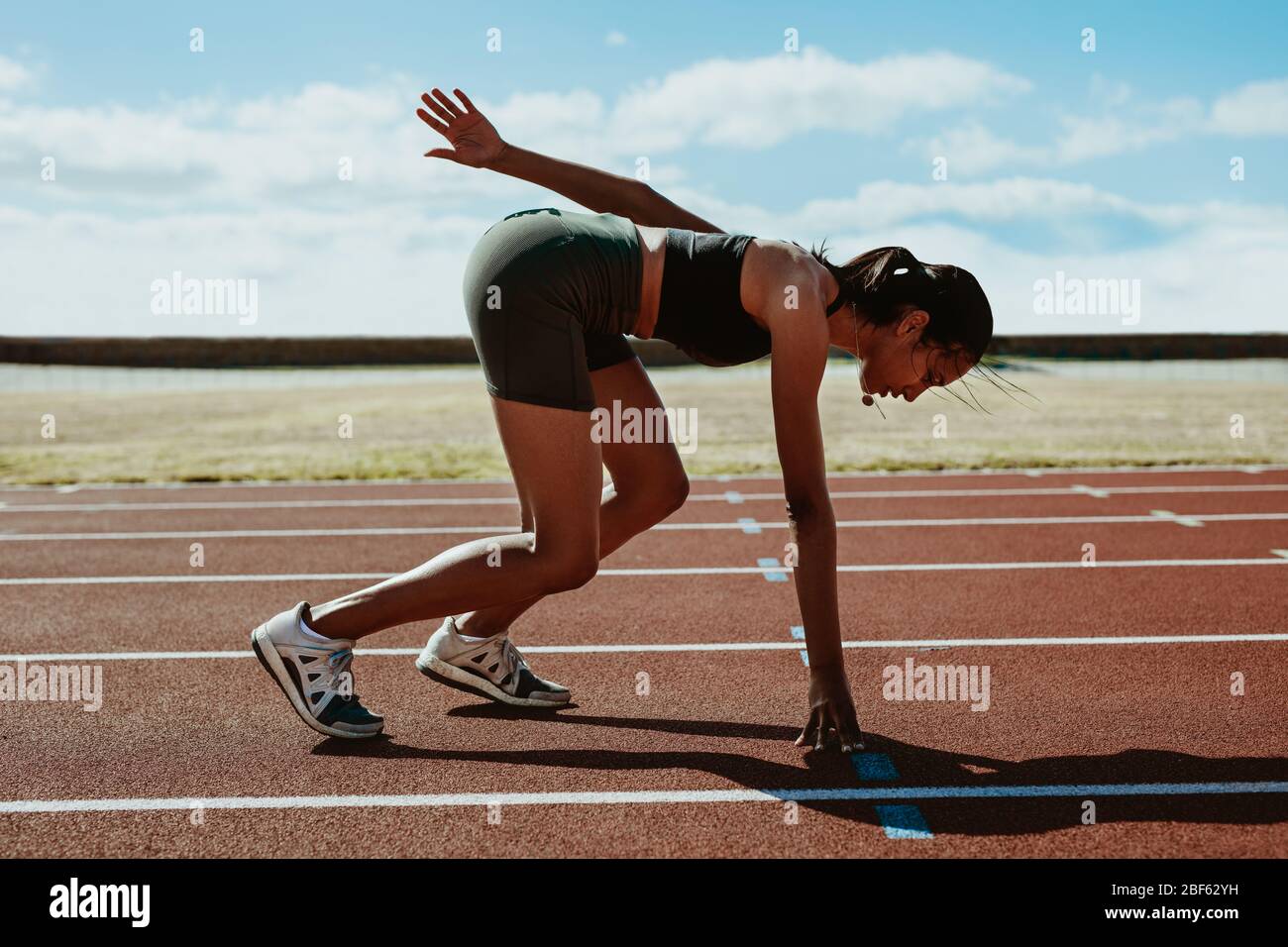 Side View Of Female Runner Getting Ready At The Start Line On Running