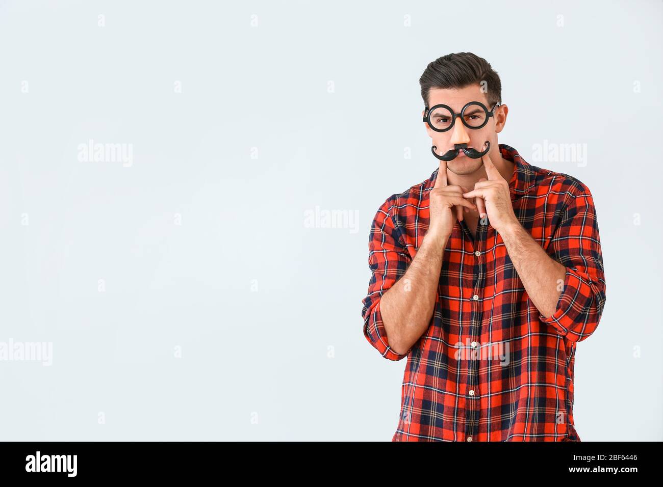 Man in funny disguise on light background. April fools' day celebration ...