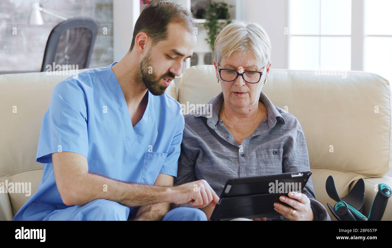 Male assistant teaching senior retired elderly old woman how to use her ...