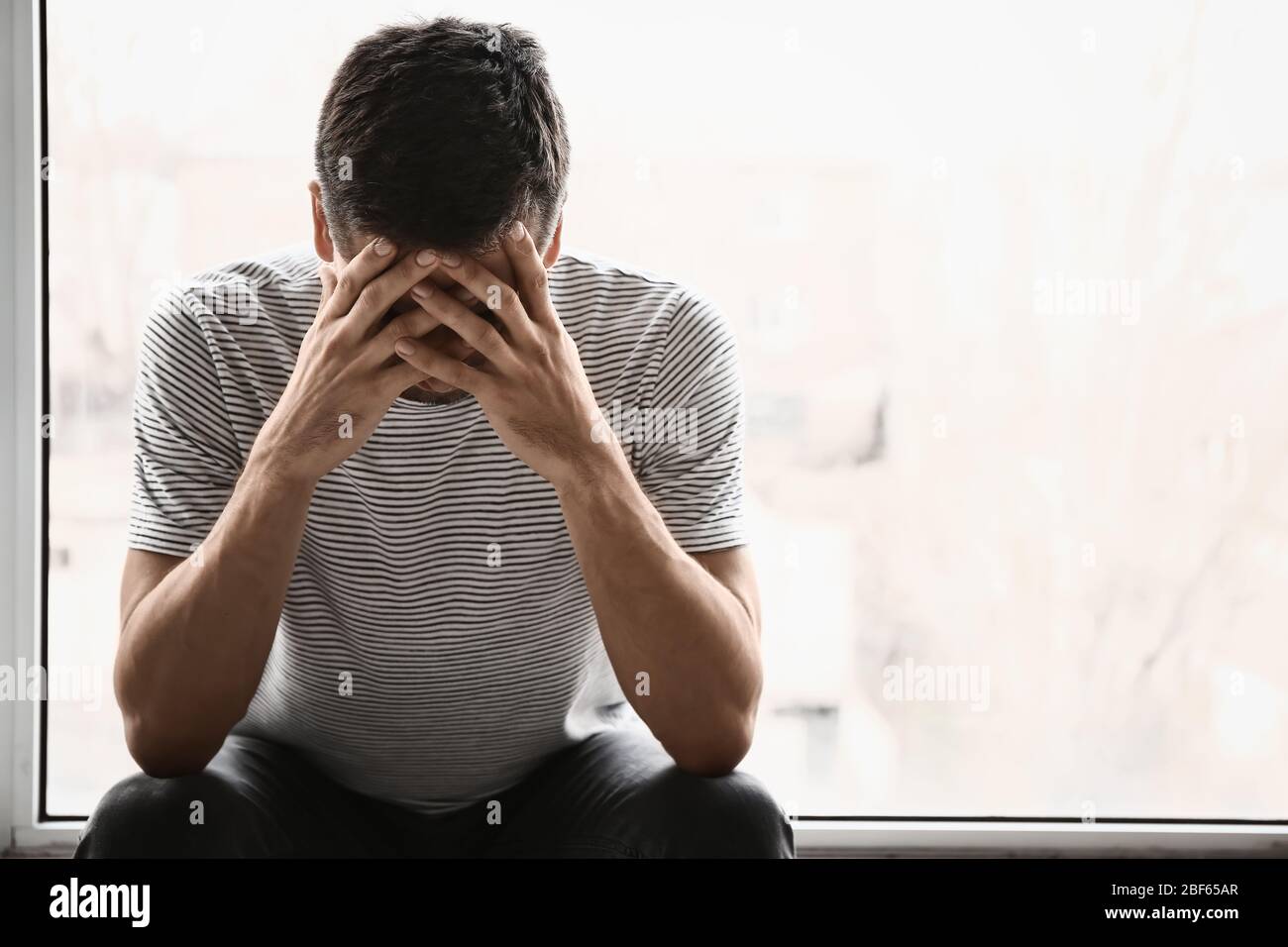 Depressed young man near window Stock Photo - Alamy