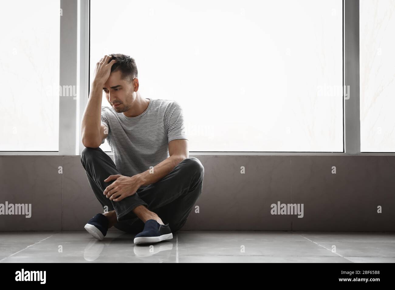Depressed young man near window Stock Photo - Alamy