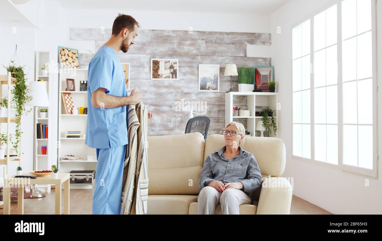 Male nurse helping senior woman getting dressed in nursing home Stock ...