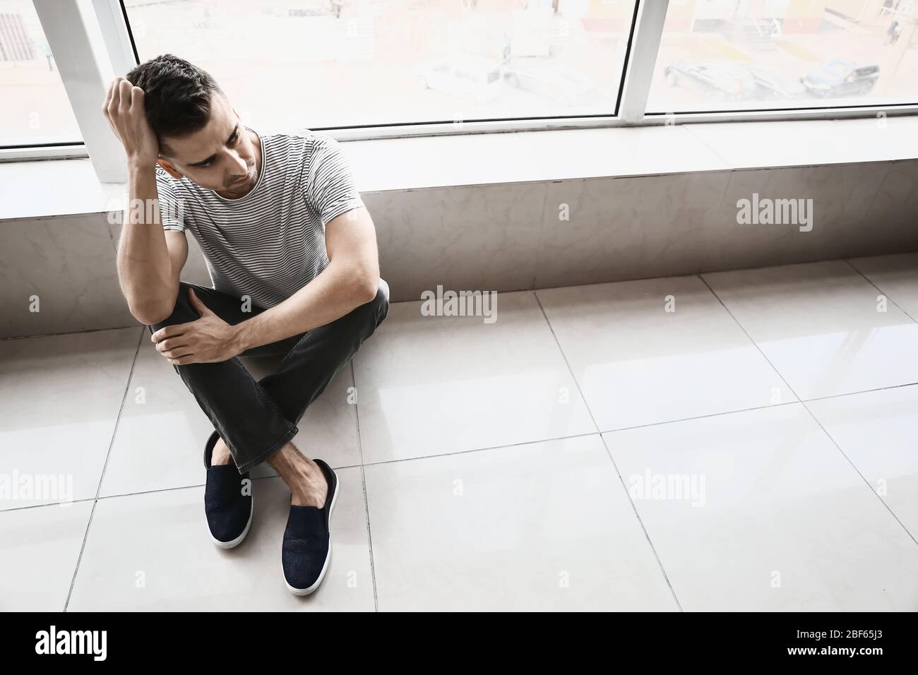 Depressed young man near window Stock Photo - Alamy