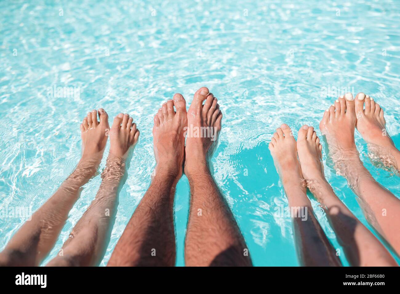 Close up of four people's legs by pool side Stock Photo - Alamy