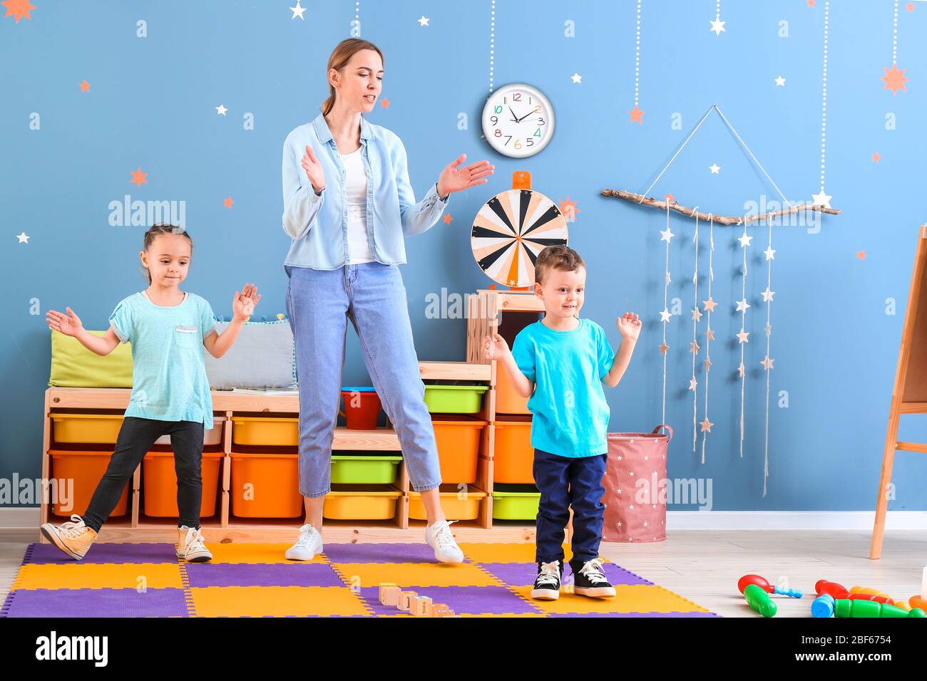 Nanny and cute little children dancing at home Stock Photo - Alamy