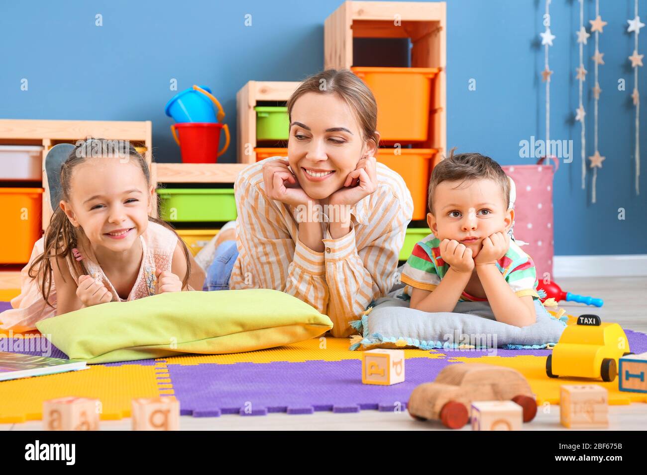 Nanny and cute little children playing at home Stock Photo - Alamy