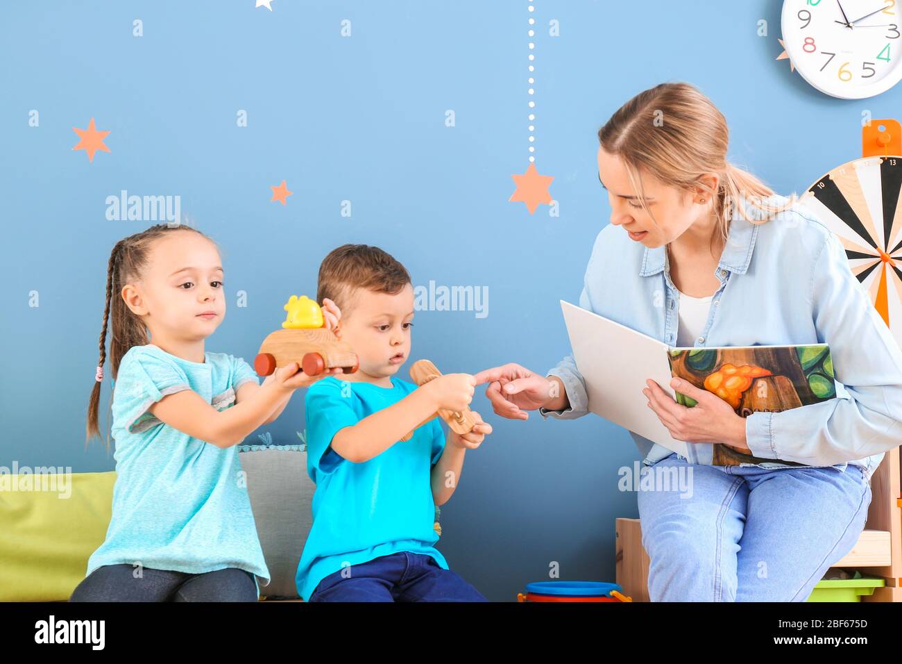 Nanny and cute little children reading book at home Stock Photo - Alamy