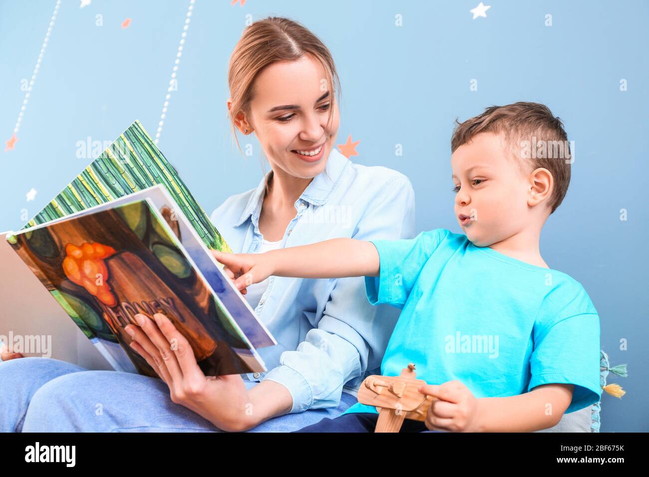 Nanny and cute little boy reading book at home Stock Photo - Alamy
