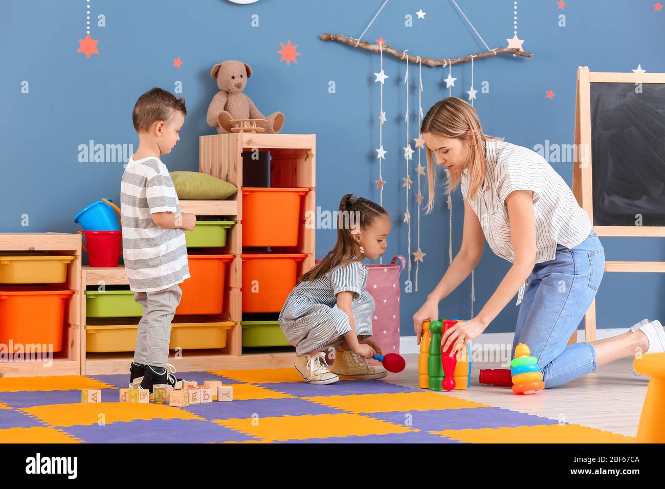 Nanny and cute little children playing at home Stock Photo - Alamy