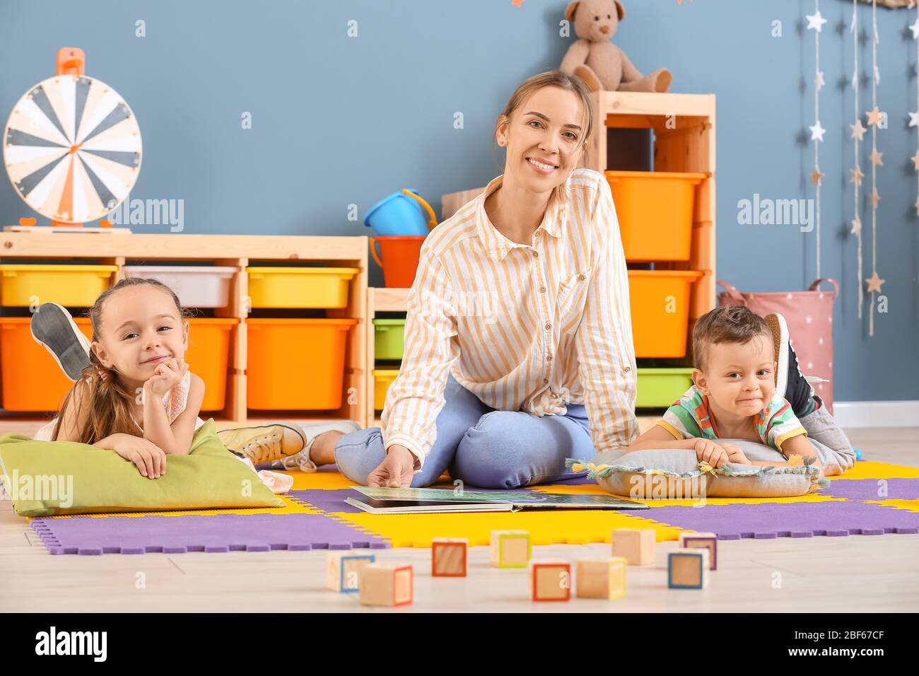 Nanny and cute little children playing at home Stock Photo - Alamy