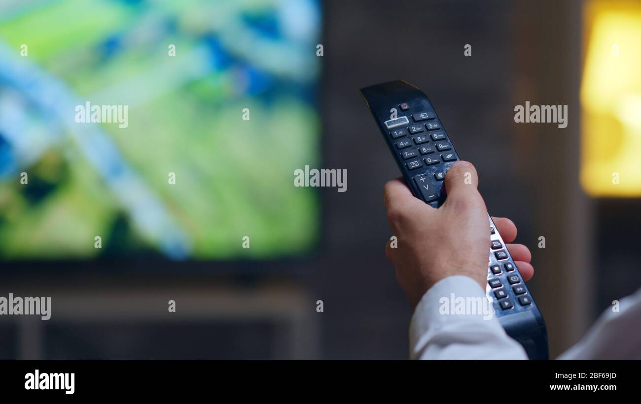 Back view of entrepreneur switching tv programs using remote control ...