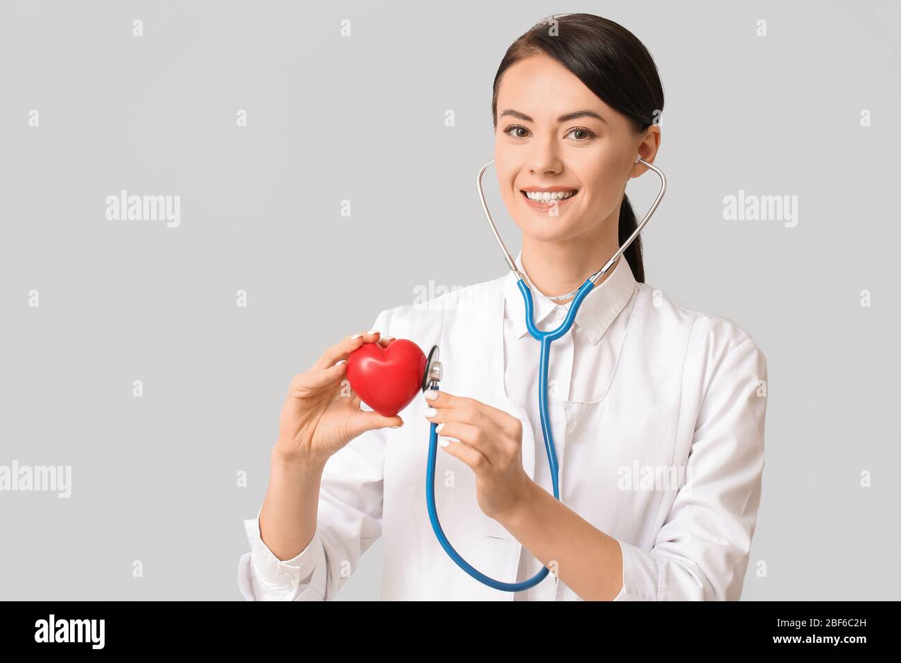 Female cardiologist on light background Stock Photo - Alamy