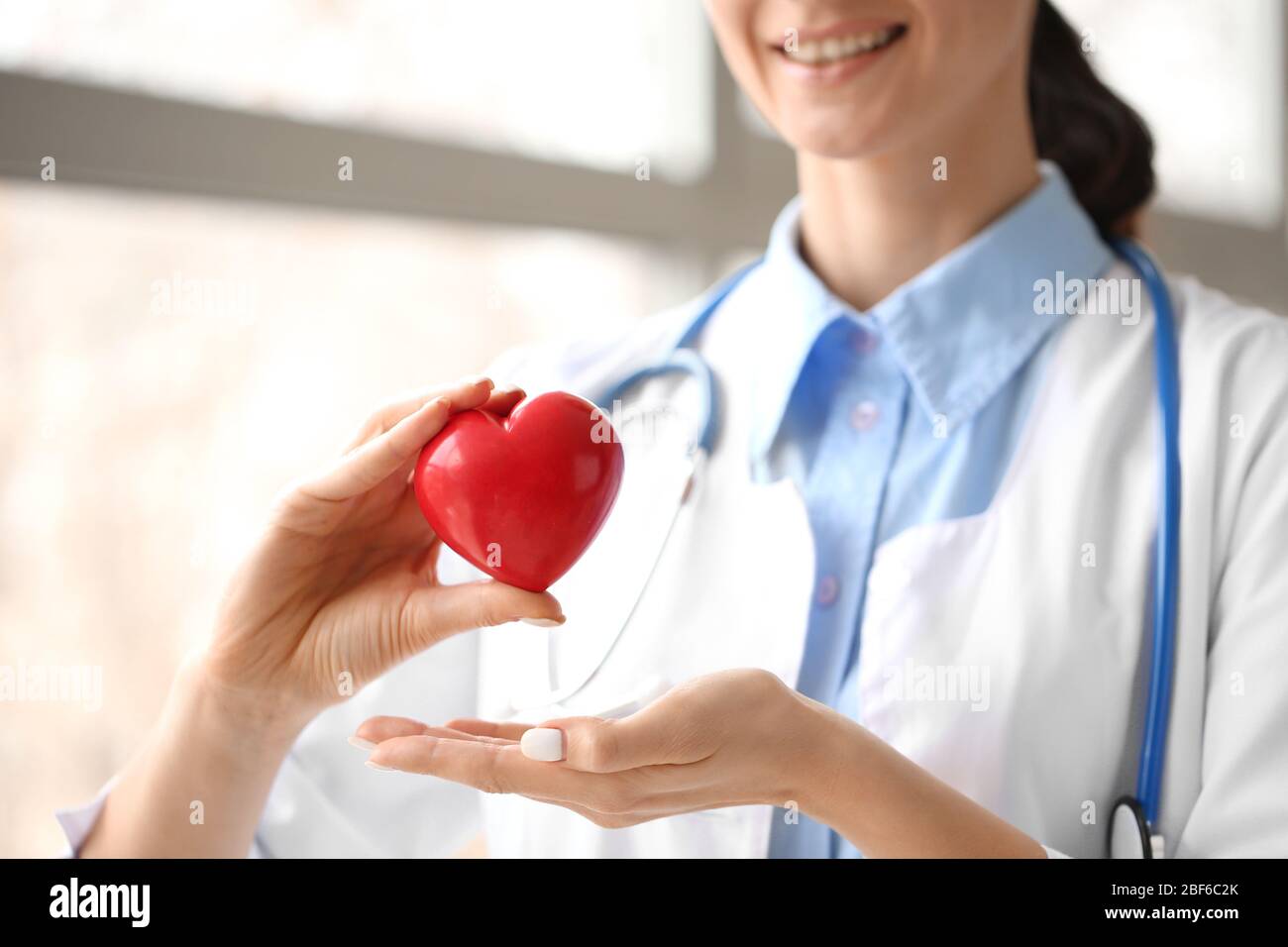 Female cardiologist with red heart in modern clinic Stock Photo - Alamy