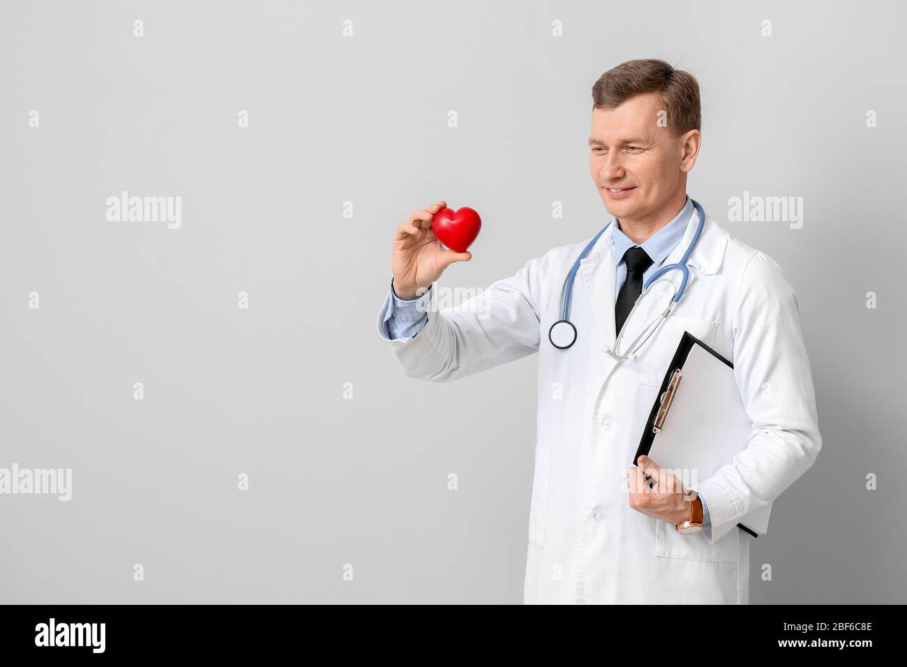 Male cardiologist on light background Stock Photo - Alamy
