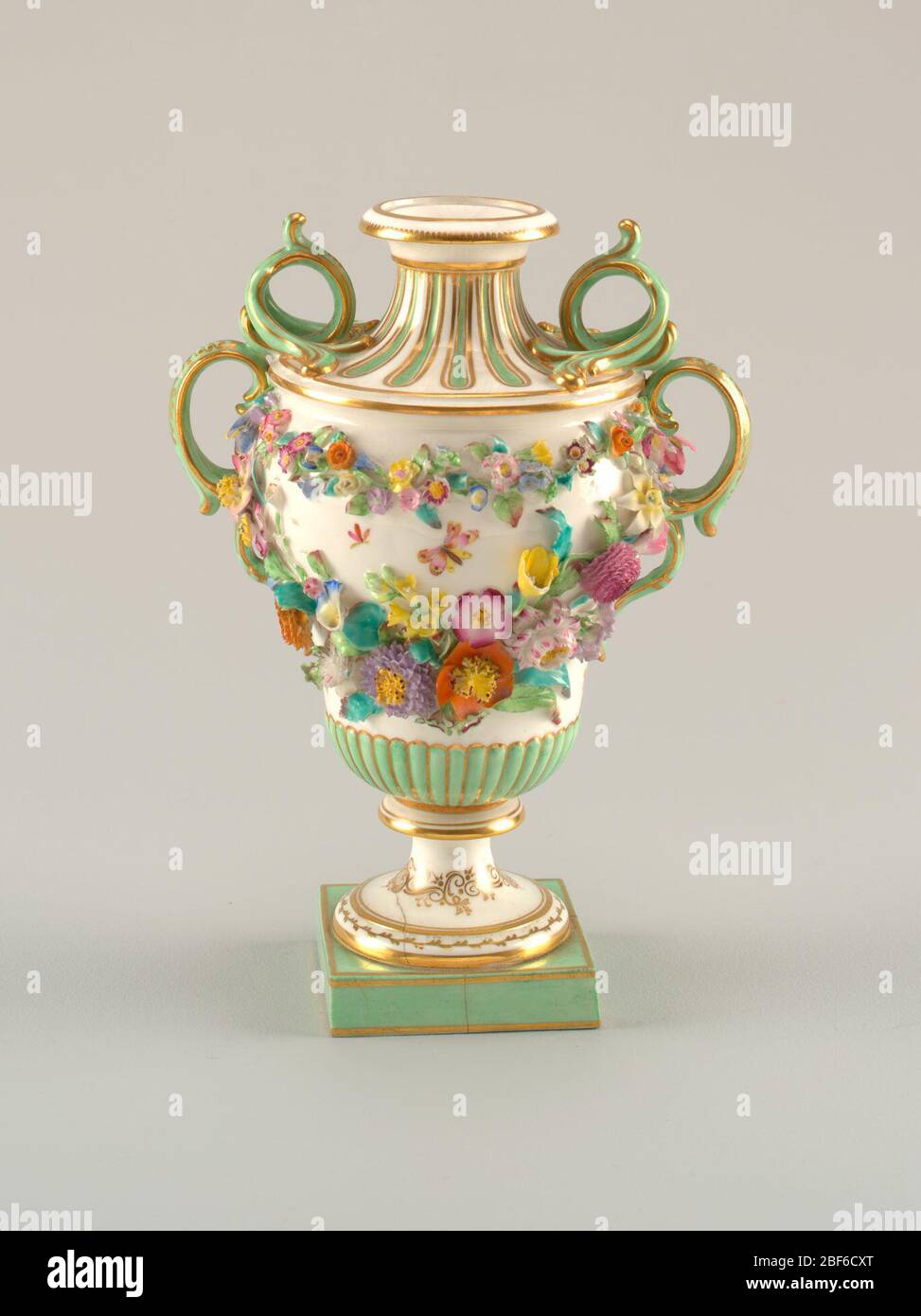 Urn with Encrusted Flowers and Butterflies. On a square pedestal, a ...