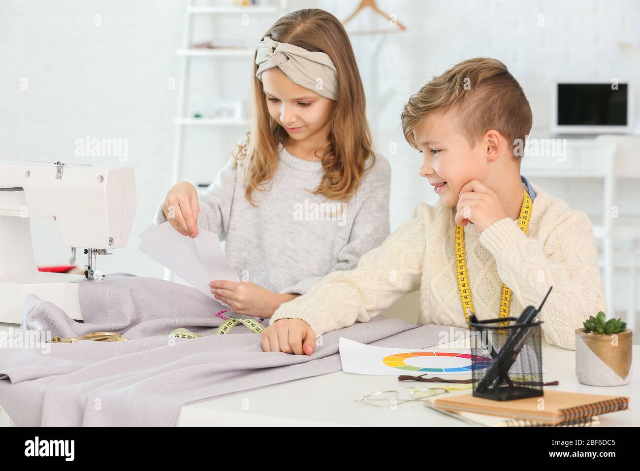 Cute little tailors working in atelier Stock Photo - Alamy