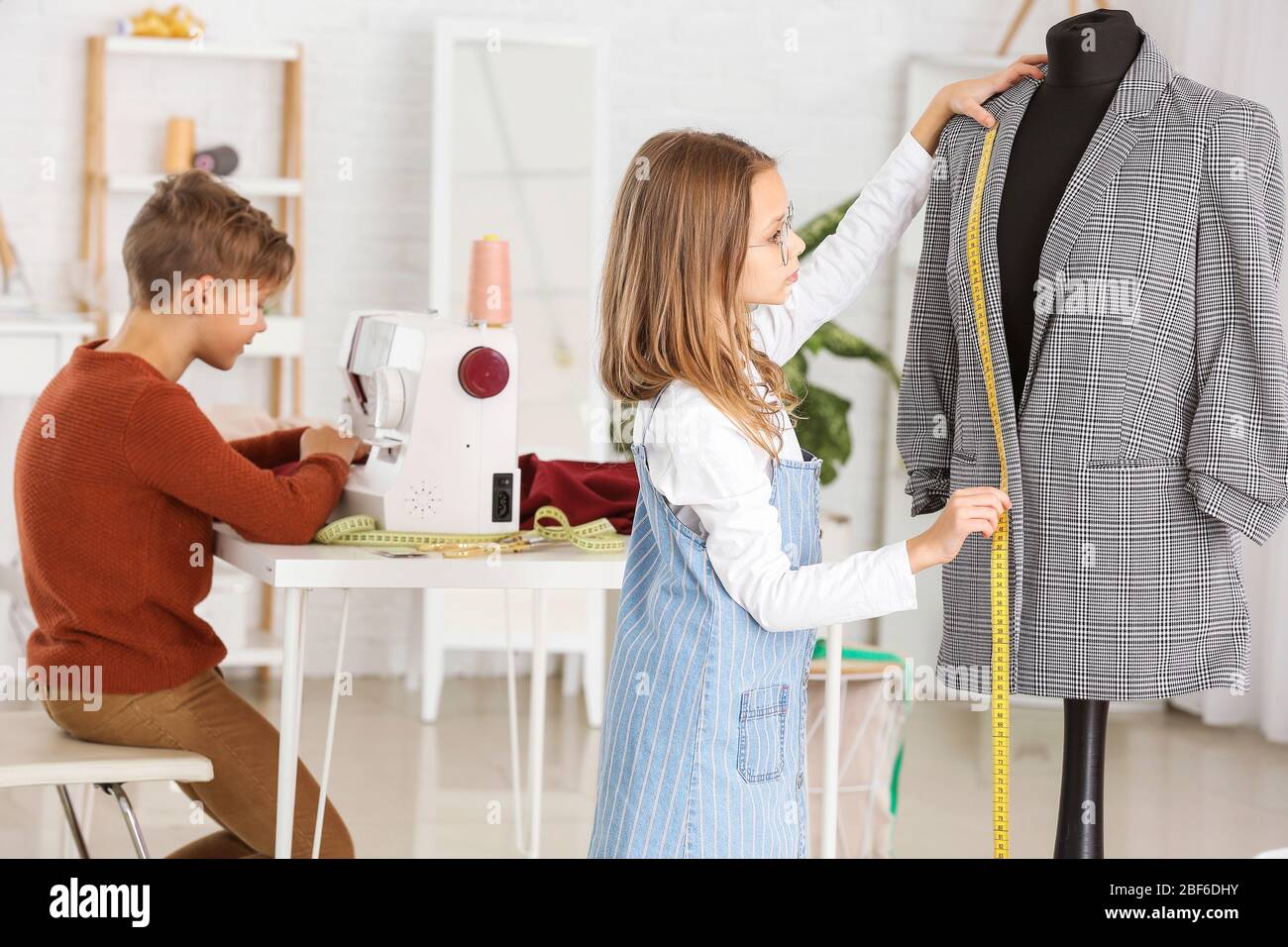 Cute little tailors working in atelier Stock Photo - Alamy