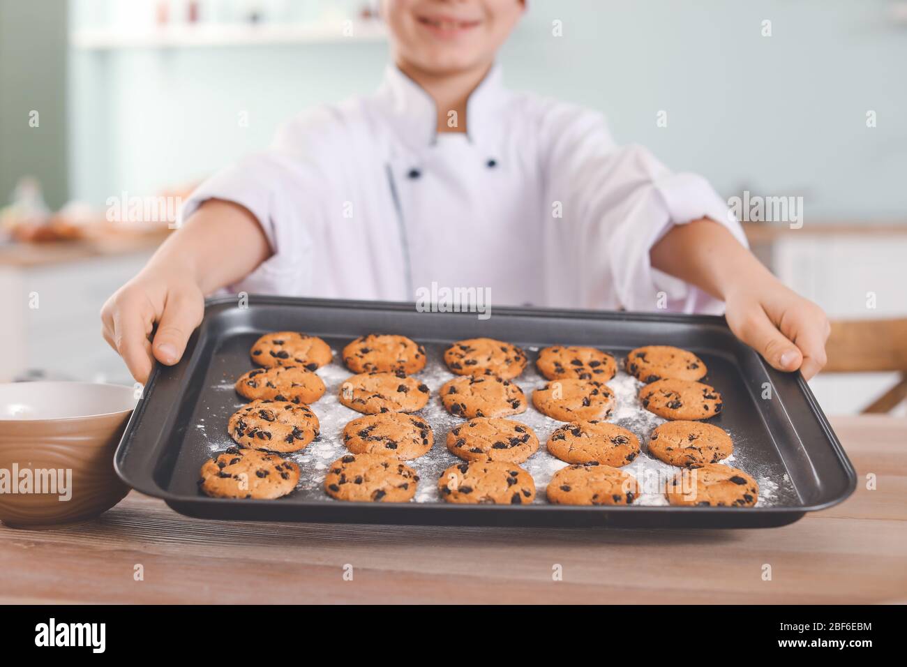 Cute little chef with cookies in kitchen Stock Photo - Alamy