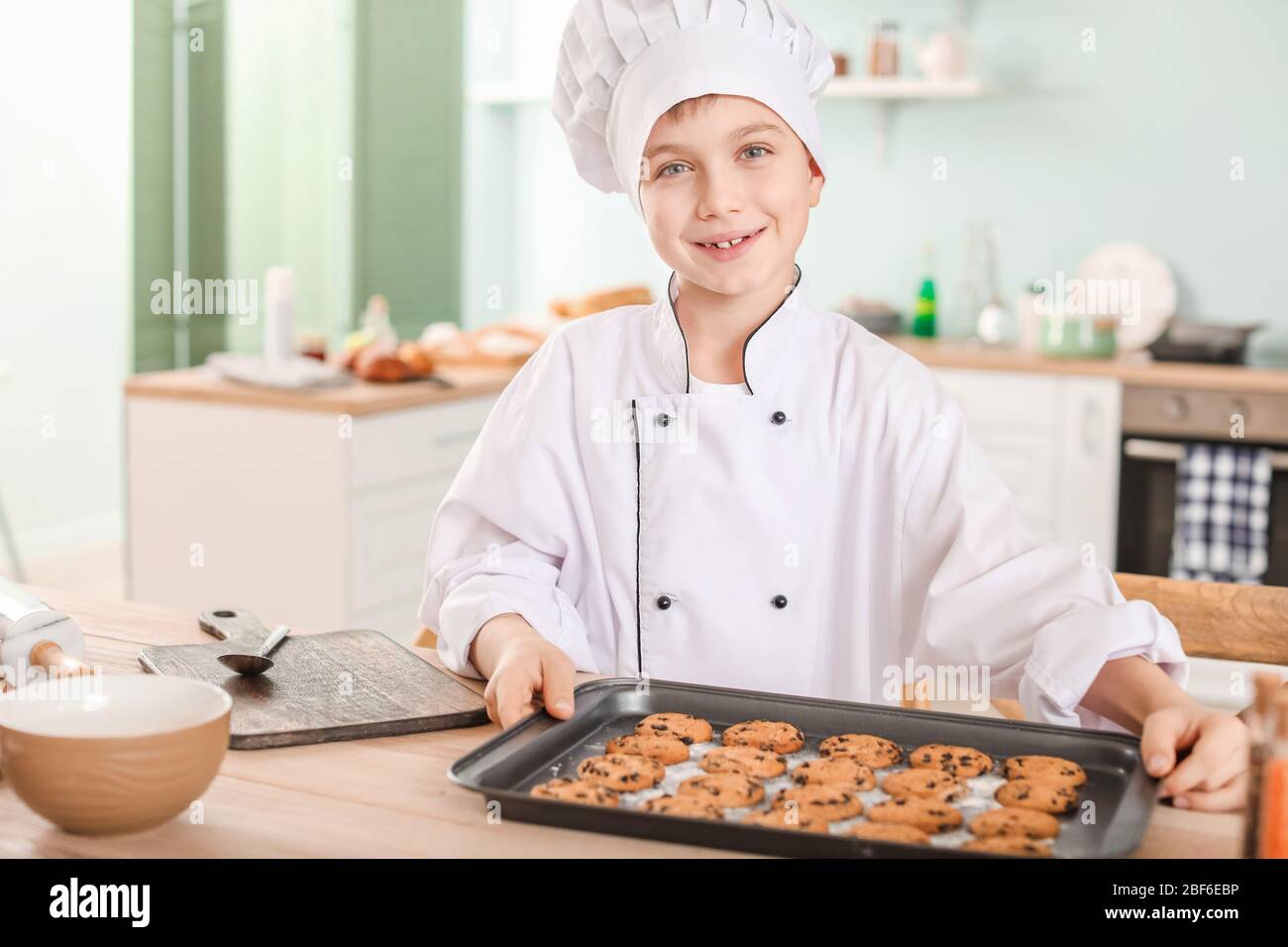 Cute little chef with cookies in kitchen Stock Photo - Alamy