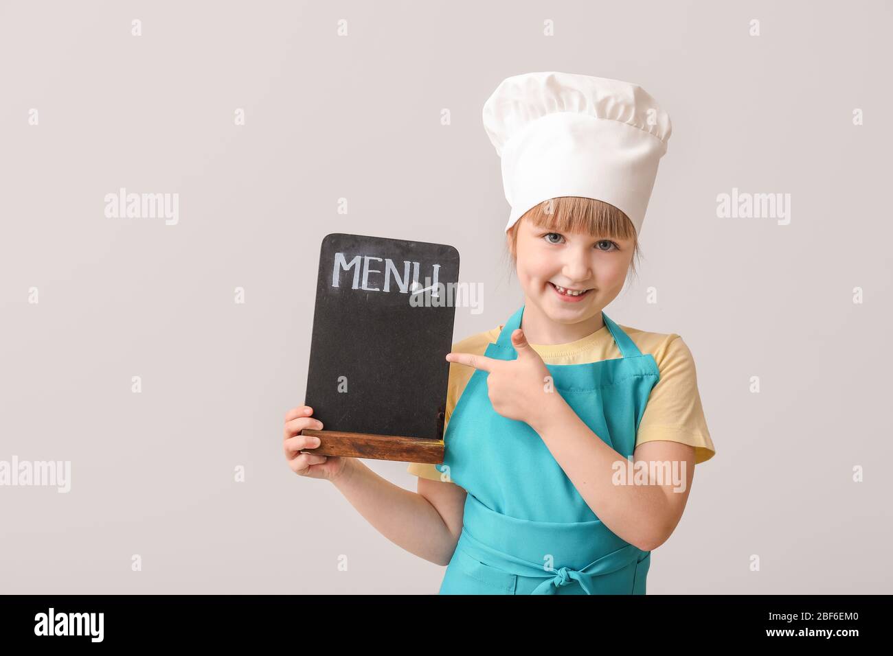 Cute little chef with menu on light background Stock Photo - Alamy