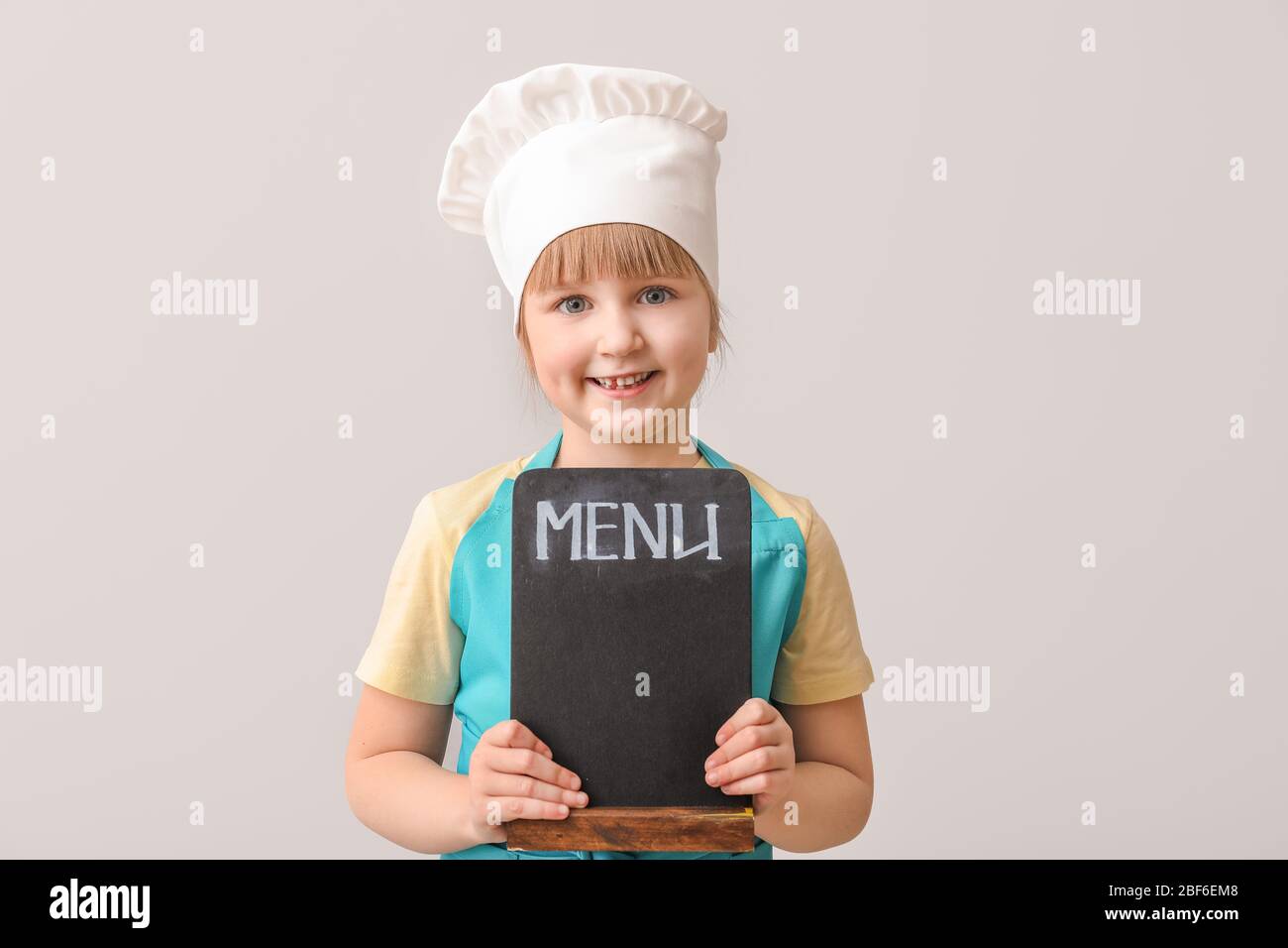 Cute little chef with menu on light background Stock Photo - Alamy