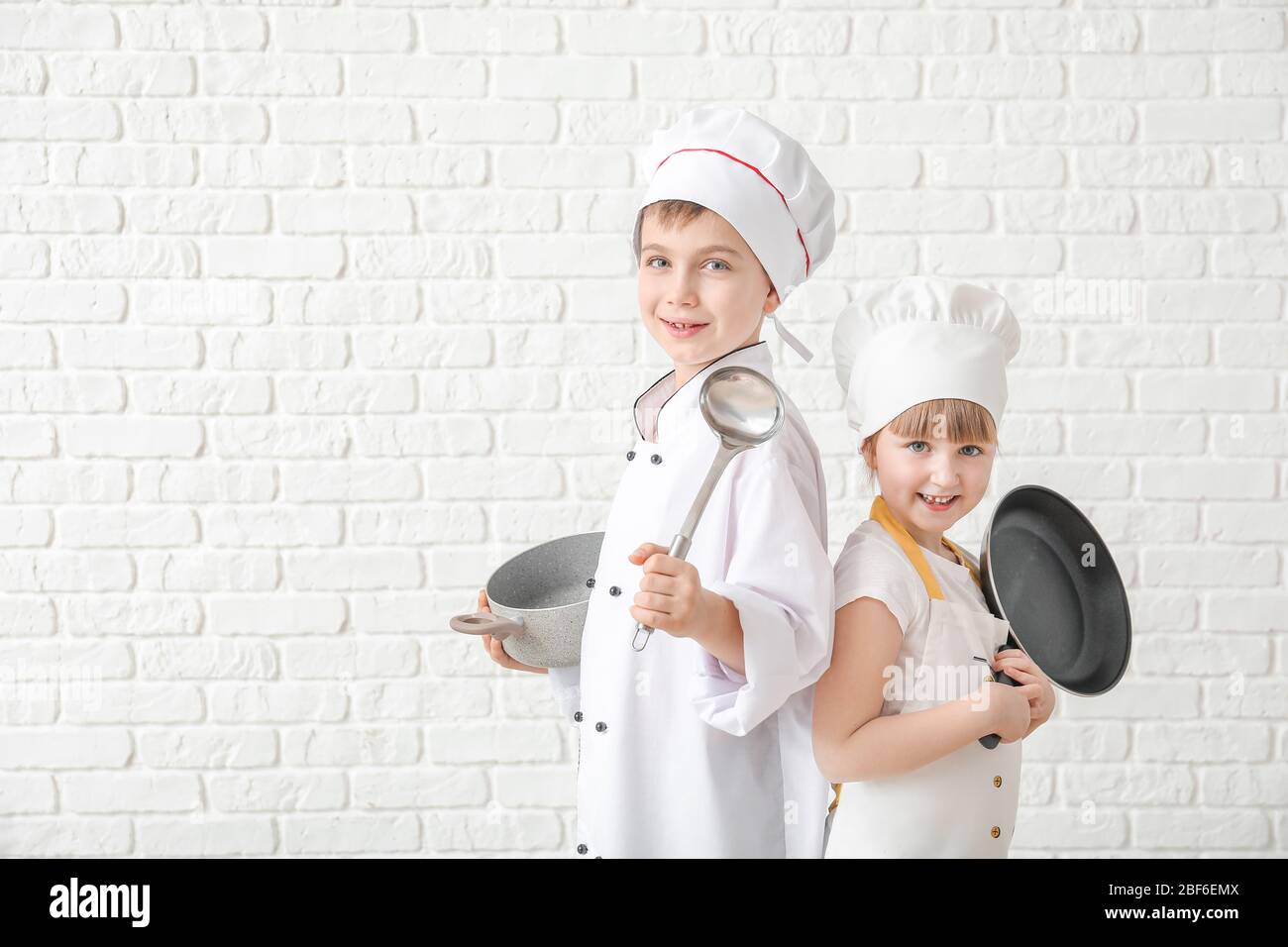 Cute little chefs with utensils on white brick background Stock Photo ...