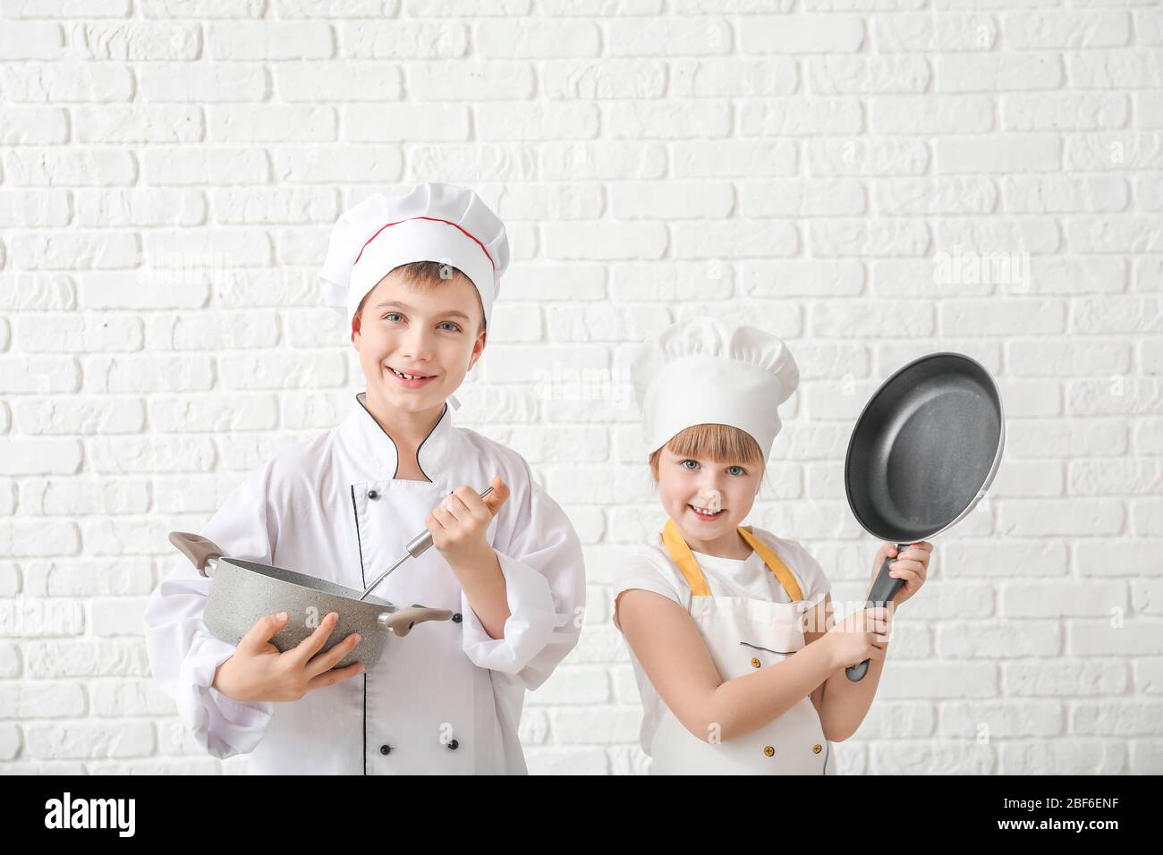 Cute little chefs with utensils on white brick background Stock Photo ...