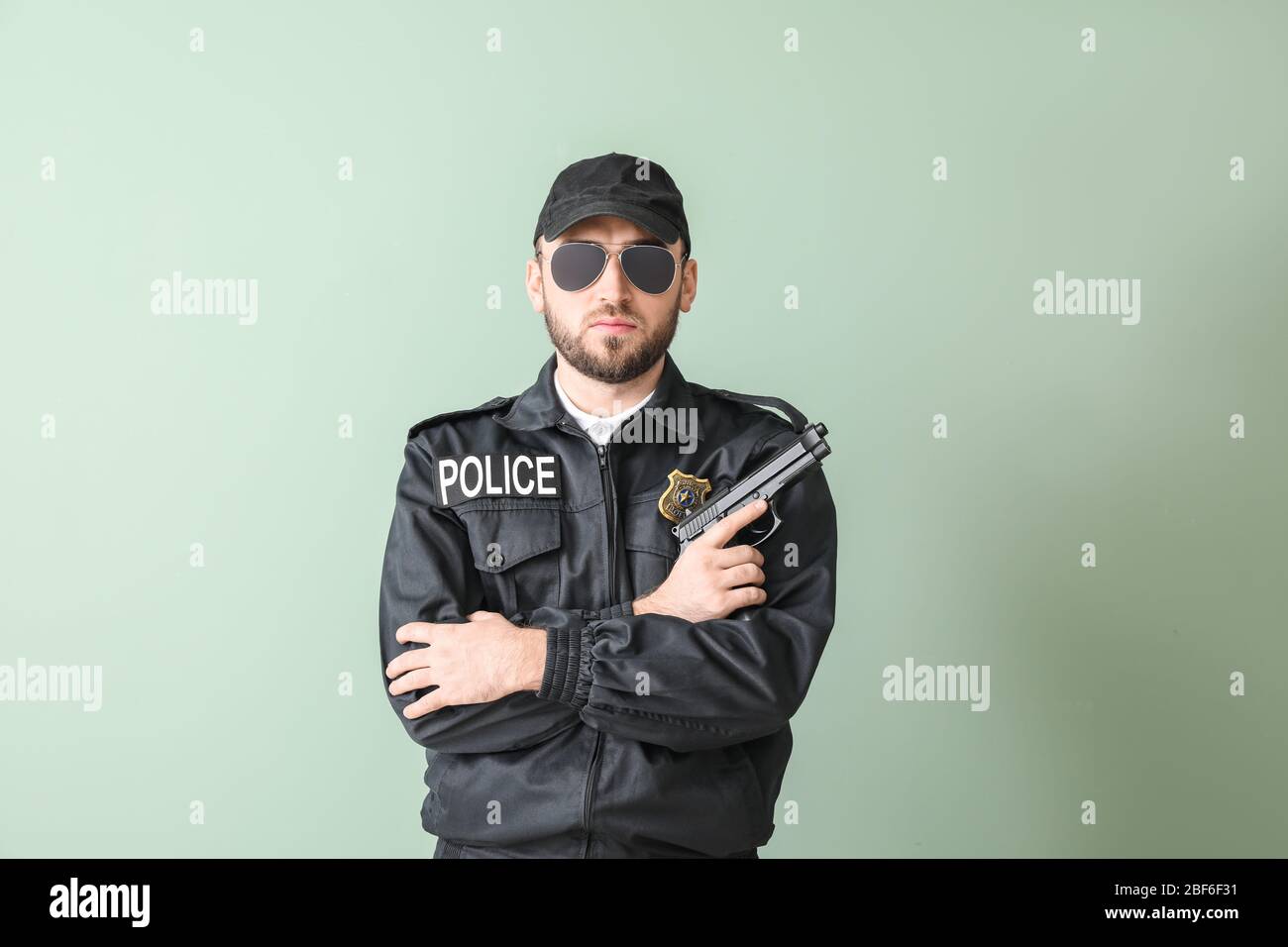 Male police officer with gun on color background Stock Photo - Alamy