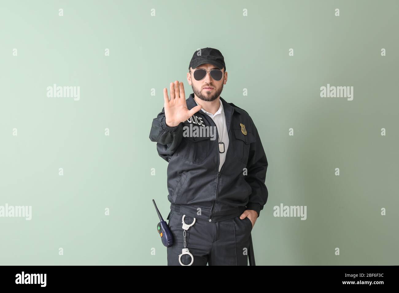 Male police officer showing STOP gesture on color background Stock ...