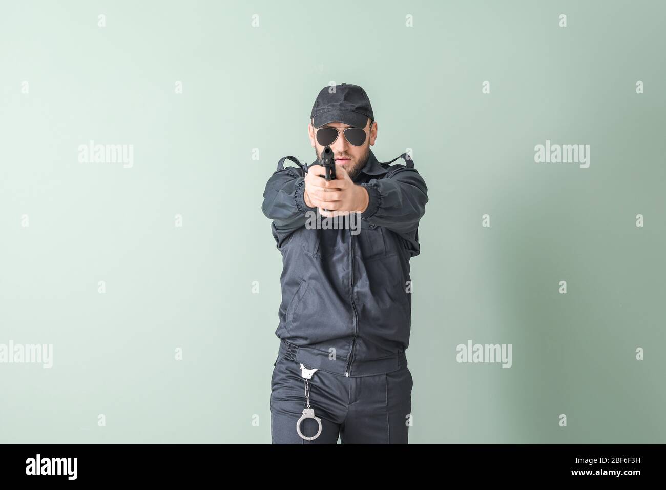Male police officer with gun on color background Stock Photo - Alamy