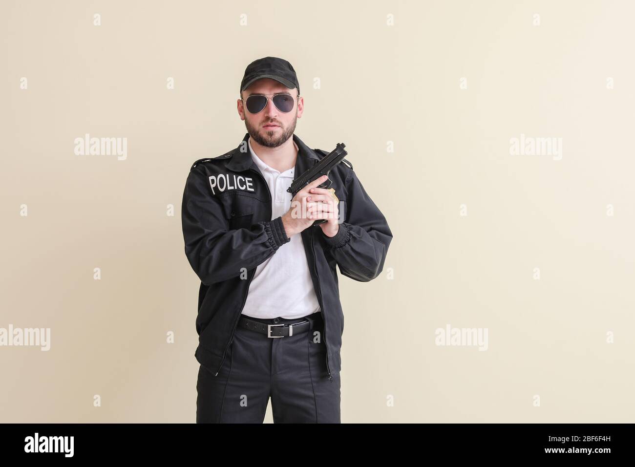 Male police officer with gun on light background Stock Photo - Alamy
