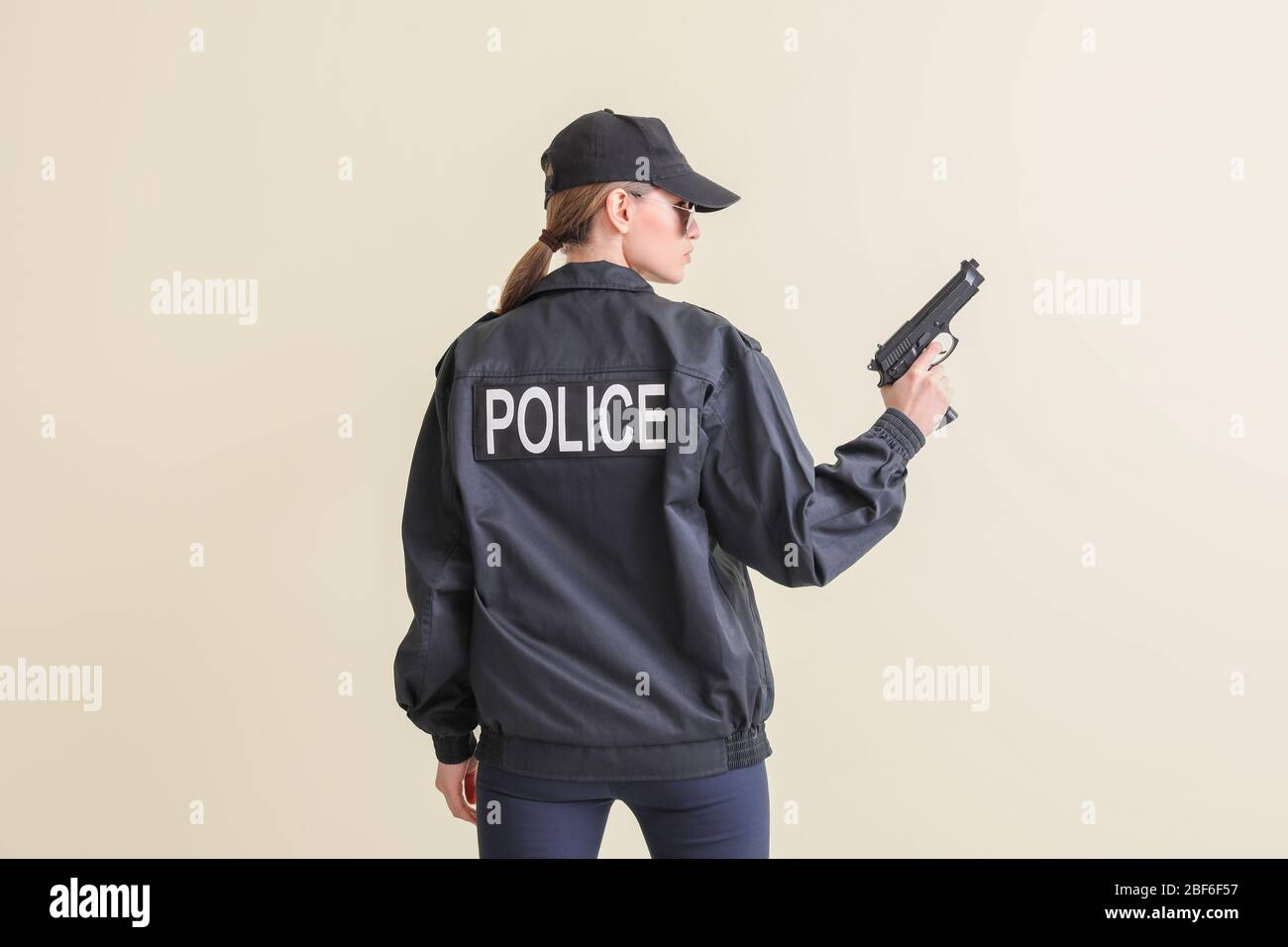 Female police officer with gun on light background Stock Photo - Alamy