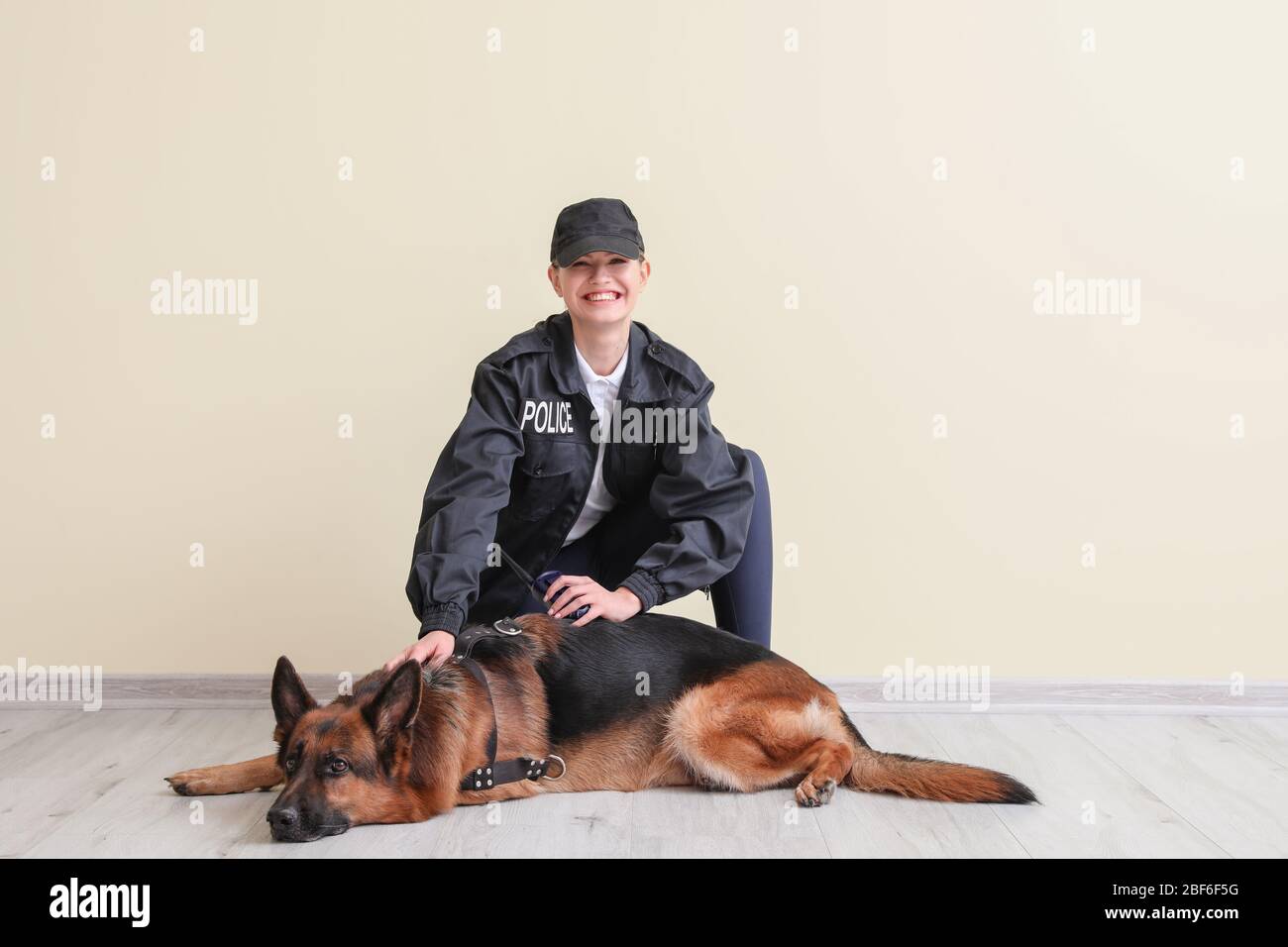 Female police officer with dog near light wall Stock Photo - Alamy