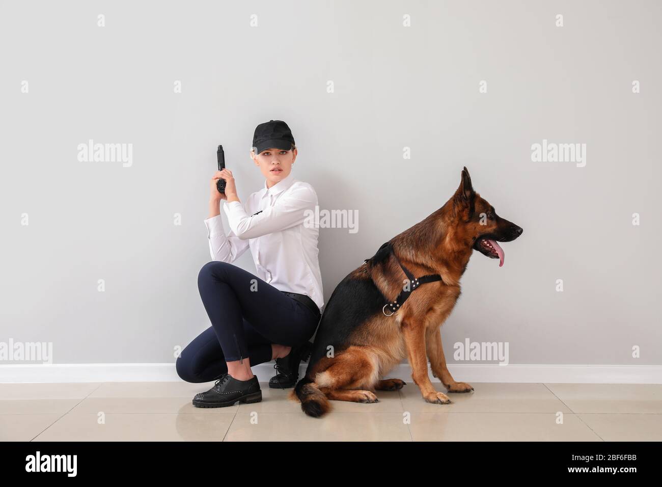 Female police officer with dog near light wall Stock Photo - Alamy
