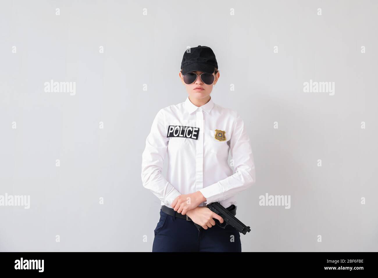Female police officer with gun on light background Stock Photo - Alamy