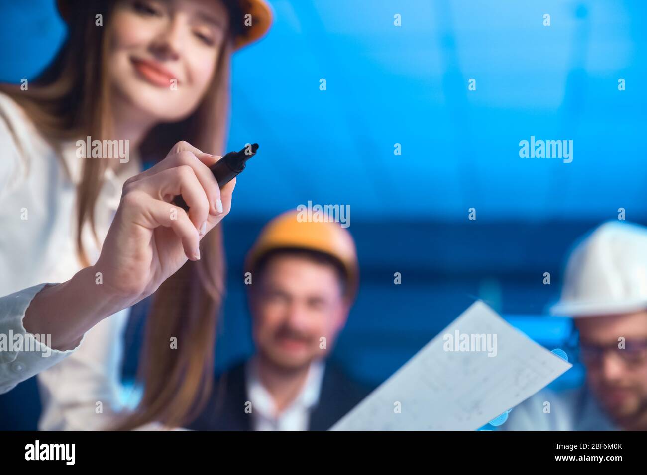 Female engineer drawing something on transparent board in office ...