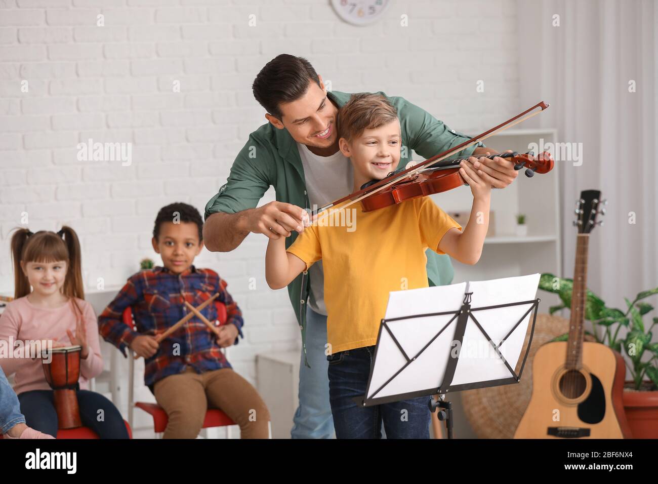 Teacher giving music lessons at school Stock Photo - Alamy