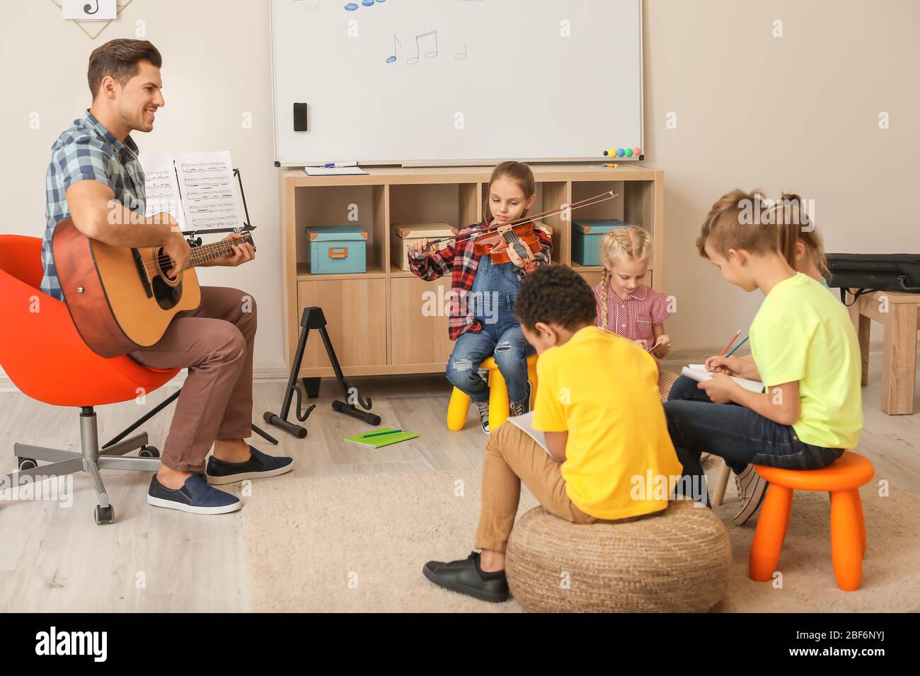 Teacher giving music lessons at school Stock Photo - Alamy