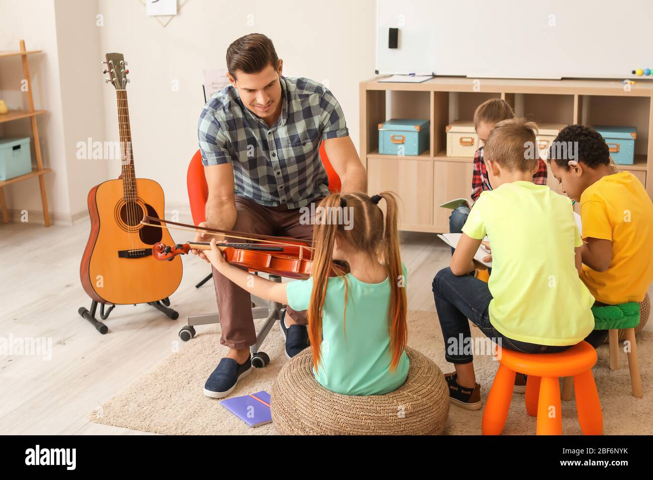 Teacher giving music lessons at school Stock Photo - Alamy